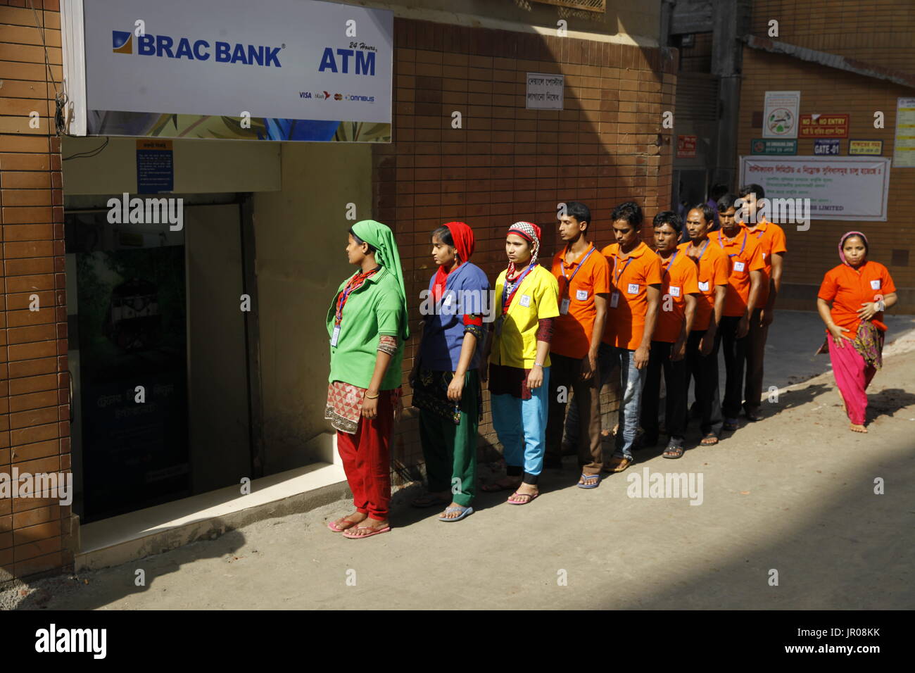 Ready-made garment workers use ATM booth services outside of a factory ...