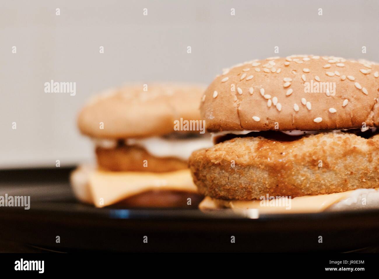 Two tasty and fresh fish burgers on black plate in kitchen. Fast food ...