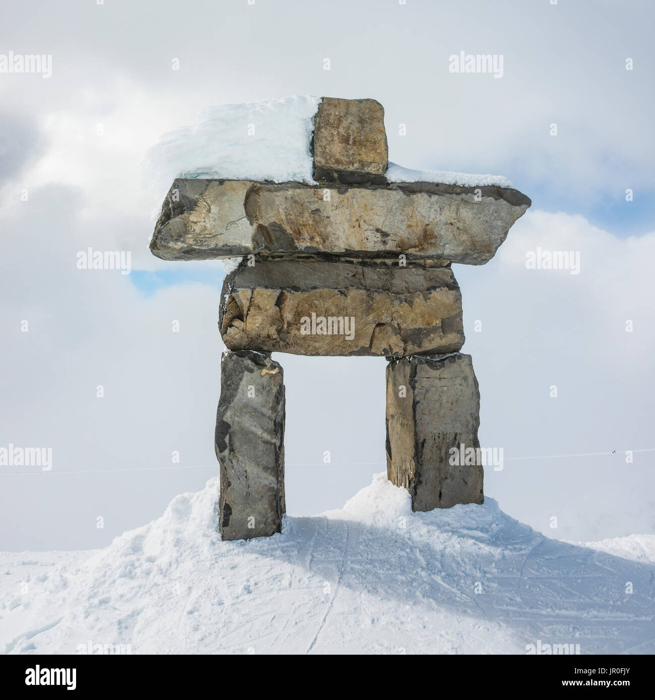 A Stone Inuksuk In The Snow Under A Cloudy Sky With A Snow Covered ...