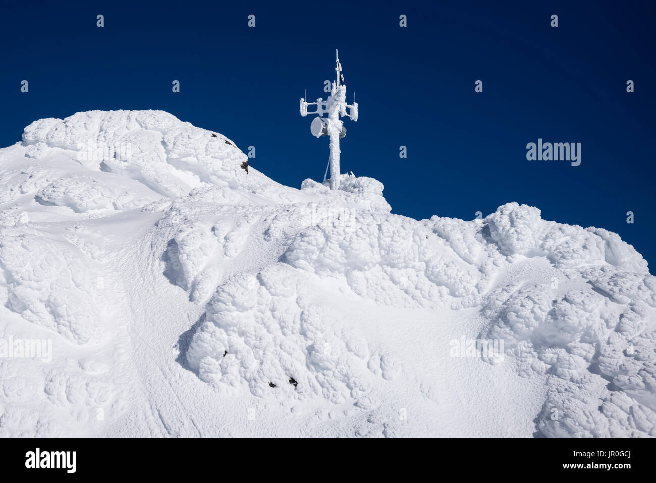 A White Transmission Tower On The Top Of A Snow Covered Mountain ...