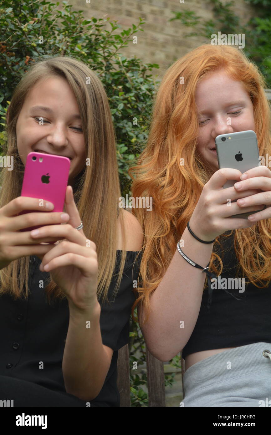 2 girls on mobile phones natural looking teen Stock Photo - Alamy