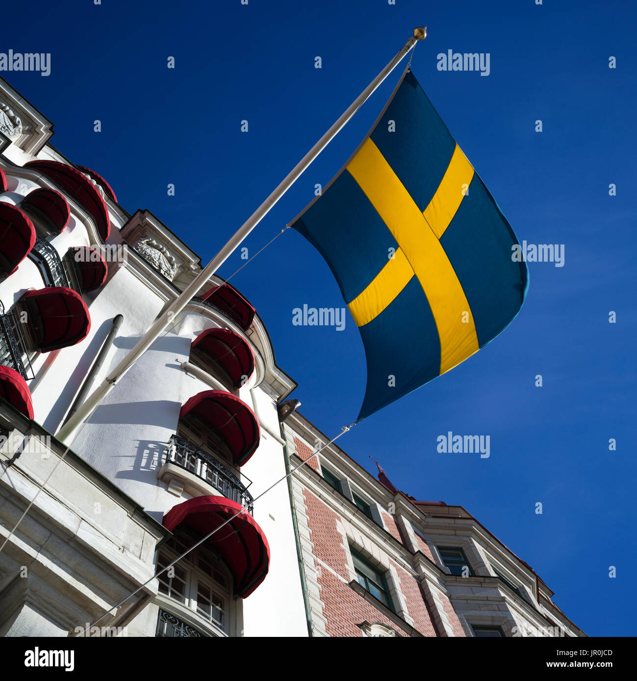 Low Angle View Of The Swedish Flag And A Building With Red Awnings Over ...