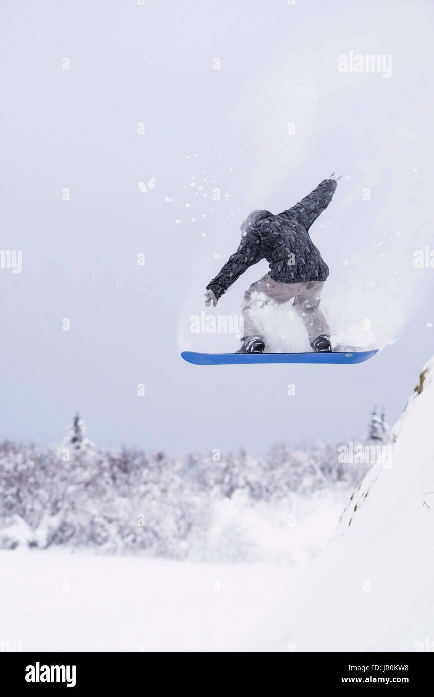 A Snowboarder Jumps Off A Mountain Cliff; Alaska, United States Of ...