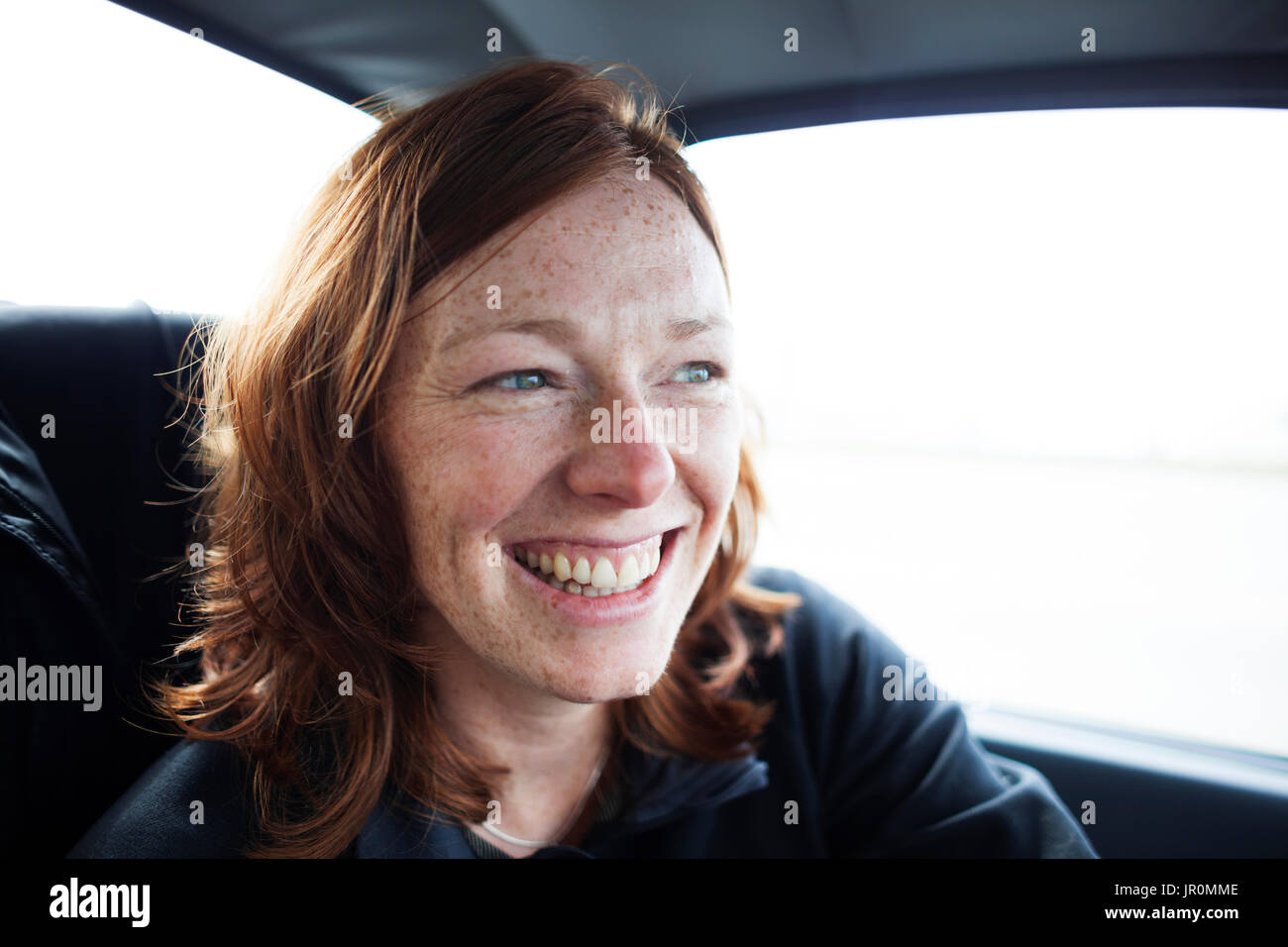 A Woman With Red Hair And Freckles Smiling While Riding In A Car ...