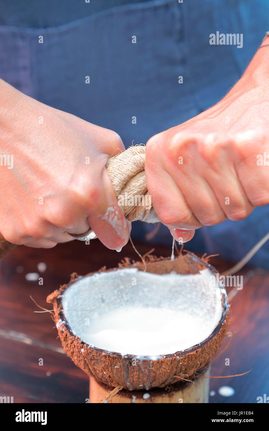 People spinning grated coconut meat to get milk, Moorea Island, French ...