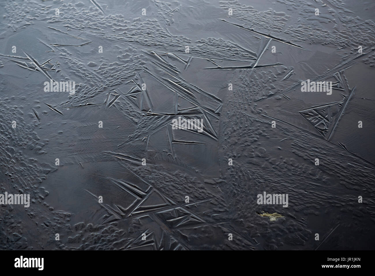 Frozen surface of a pond with formations of triangles and zig-zags due ...