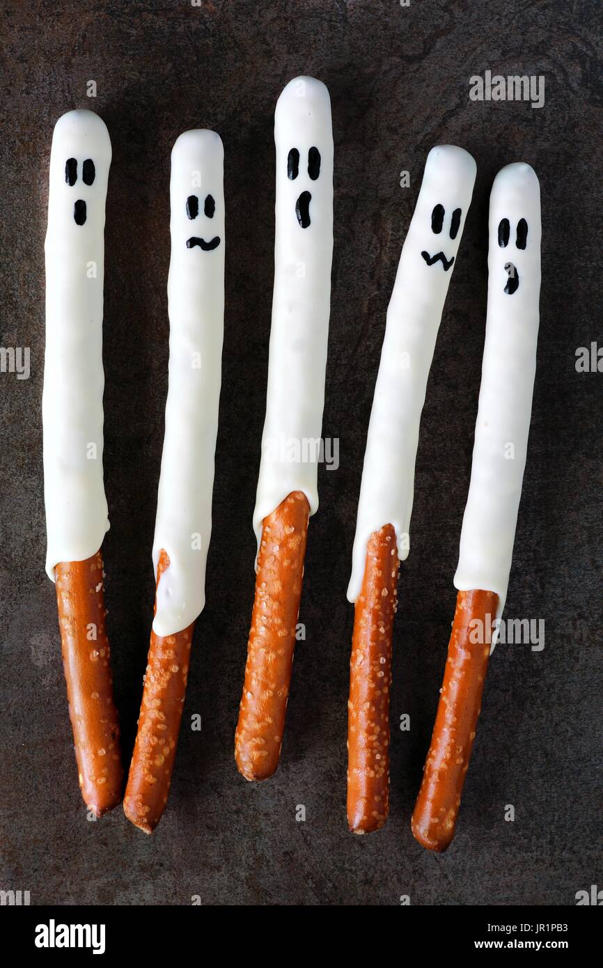 Group of Halloween ghost, candy dipped pretzel rods on black stone ...