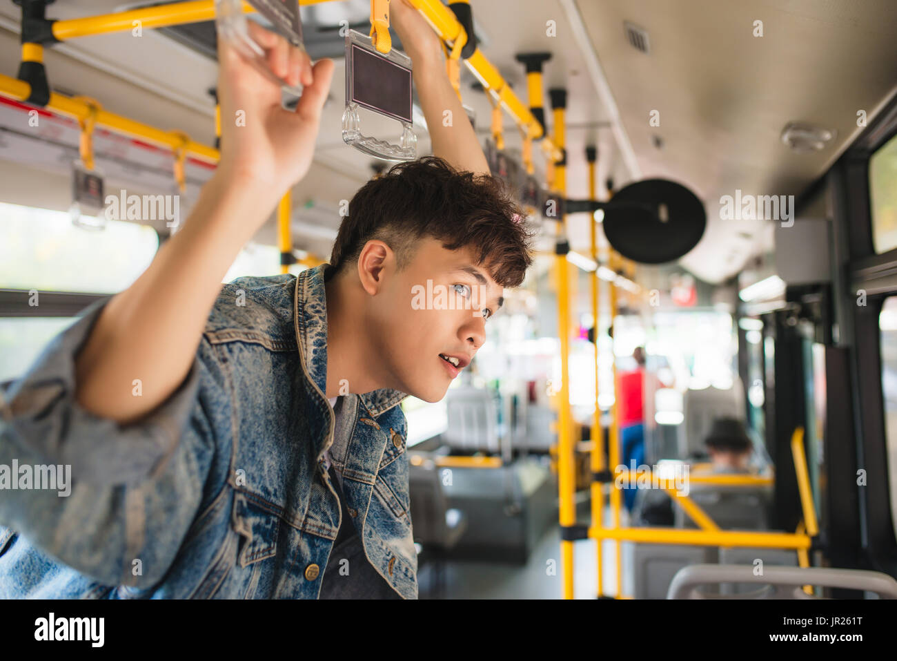 Asian man taking public transport, standing inside bus Stock Photo - Alamy