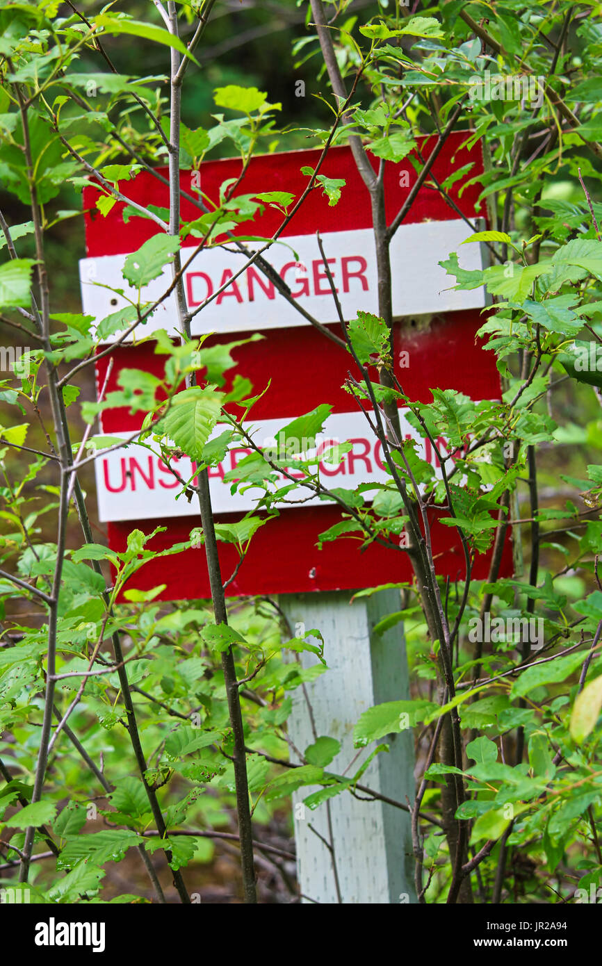 A danger, unstable ground sign obscured by trees Stock Photo - Alamy