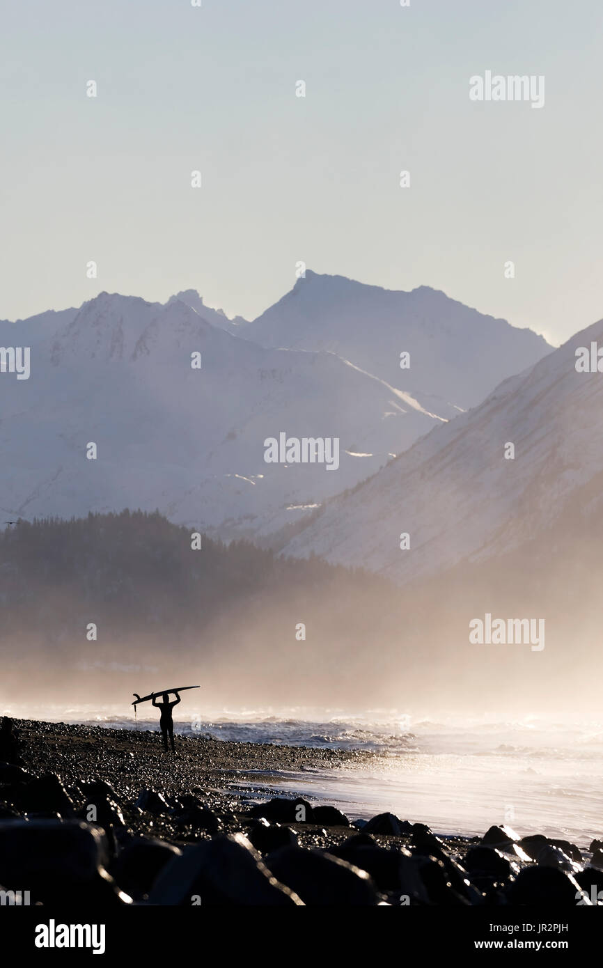 A Surfer Carries Her Surfboard Across The Beach In The Mist Along The ...