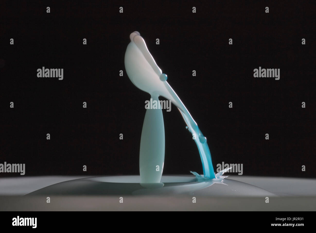 Drop of milk falling into milk on black background Stock Photo - Alamy