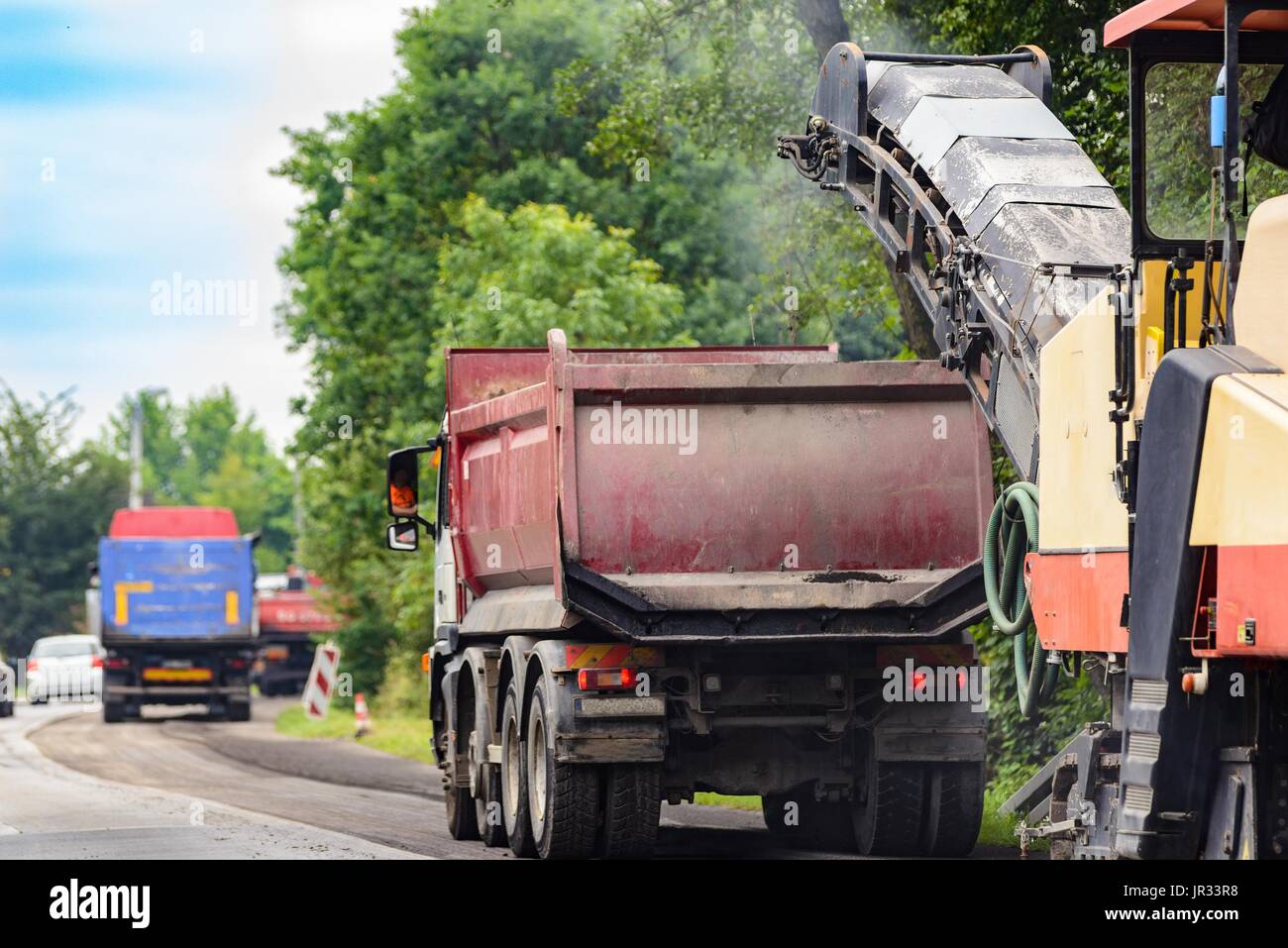 Road works. Asphalt removing machine loading powdered asphalt on the ...