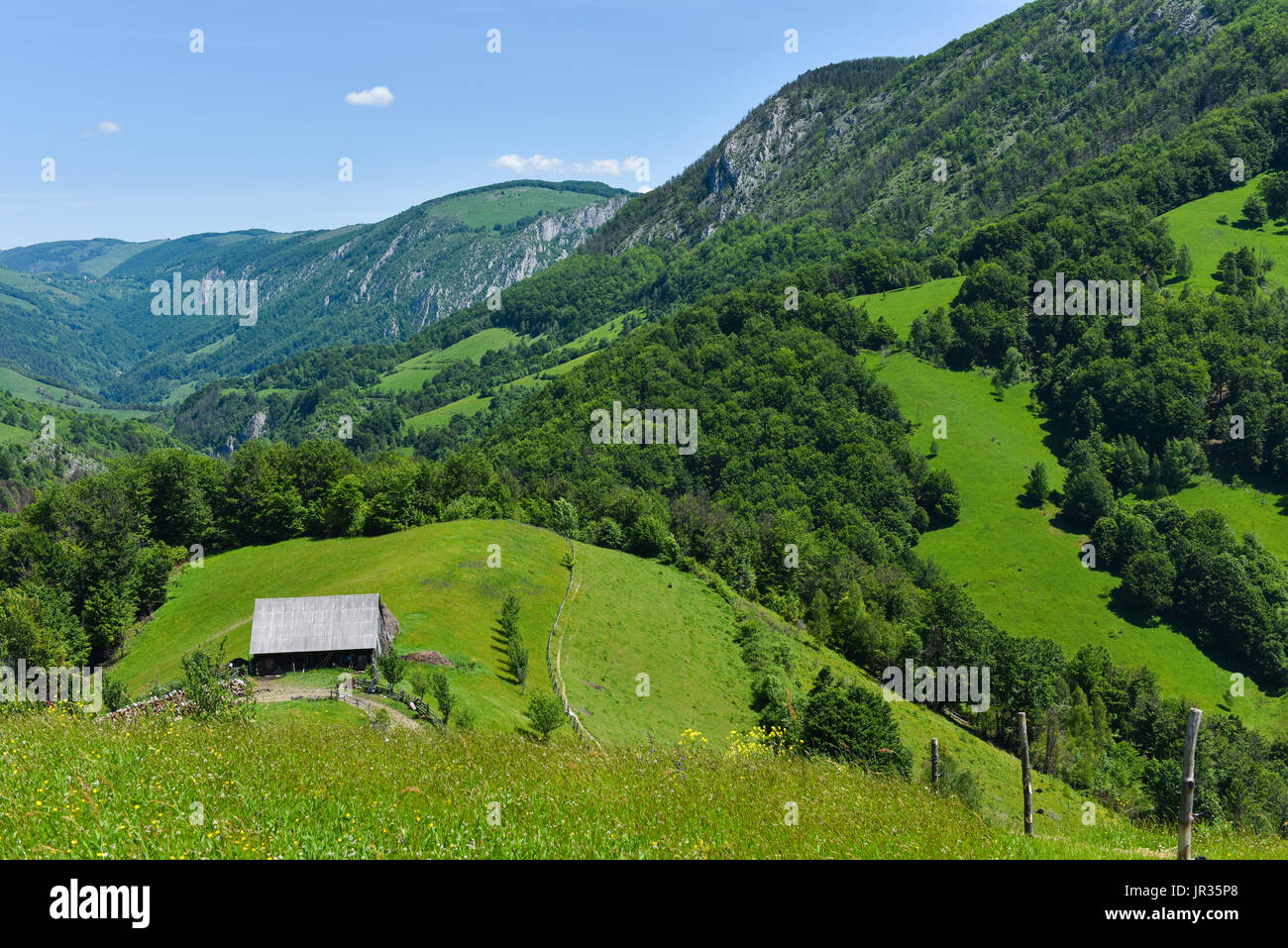 Green countryside landscape in the mountains with a small barn ...