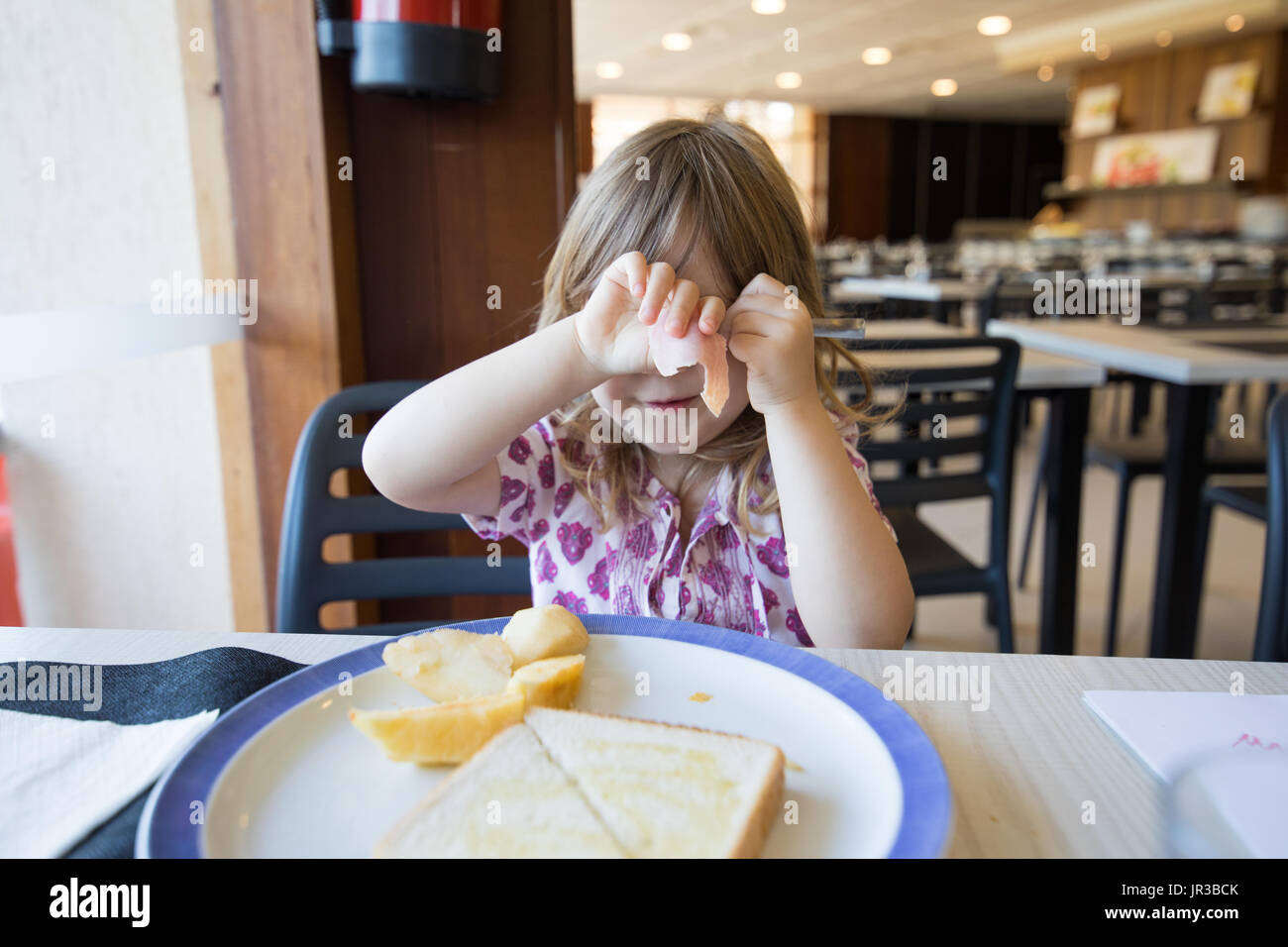 portrait of blonde caucasian child three years old, eating, hiding face ...