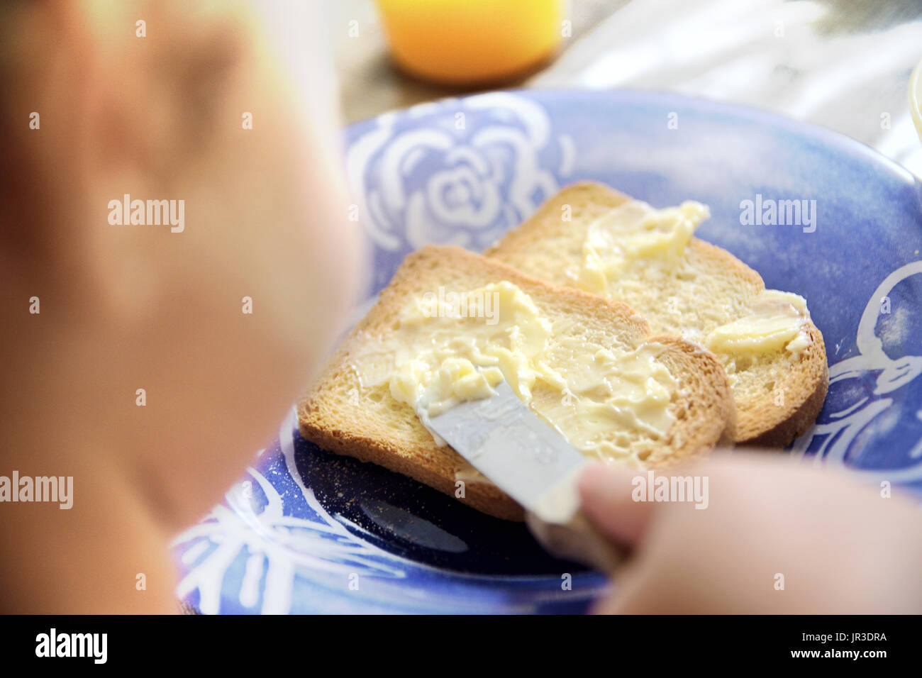 Little girl spreading some butter on toast bread Stock Photo - Alamy