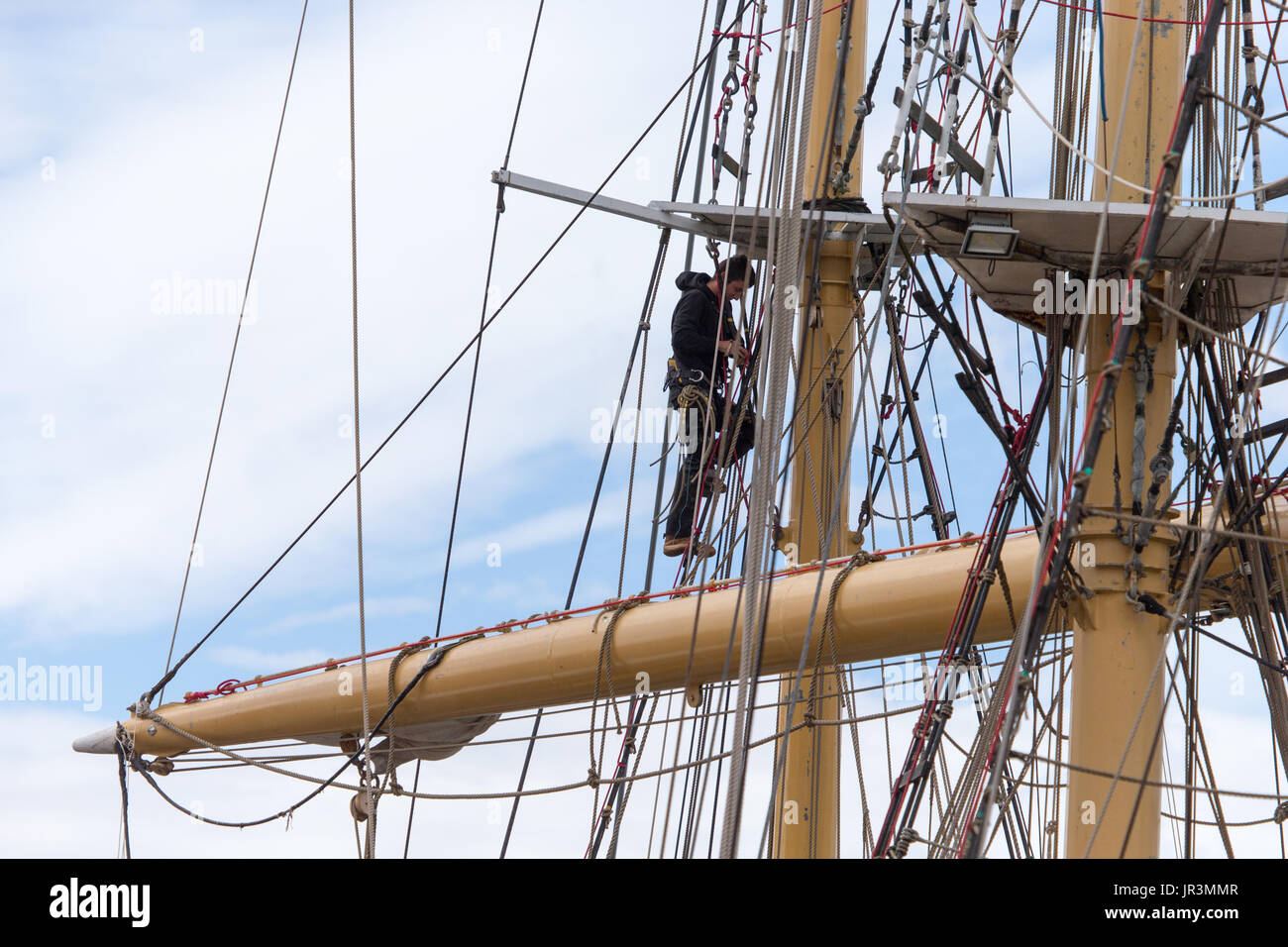 A seaman on a sail training ship working aloft on rigging repairs Stock ...