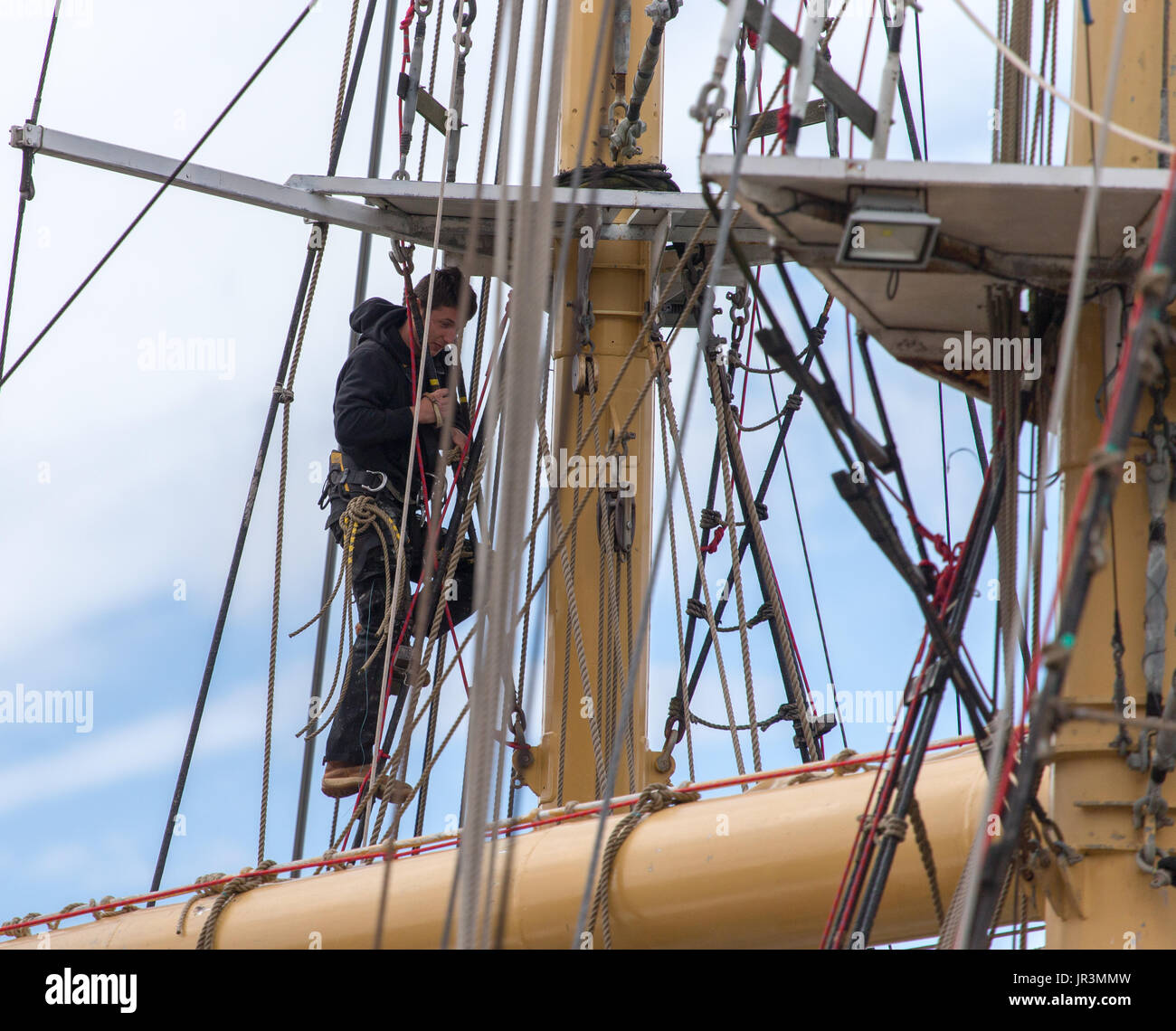 A seaman on a sail training ship working aloft on rigging repairs Stock ...