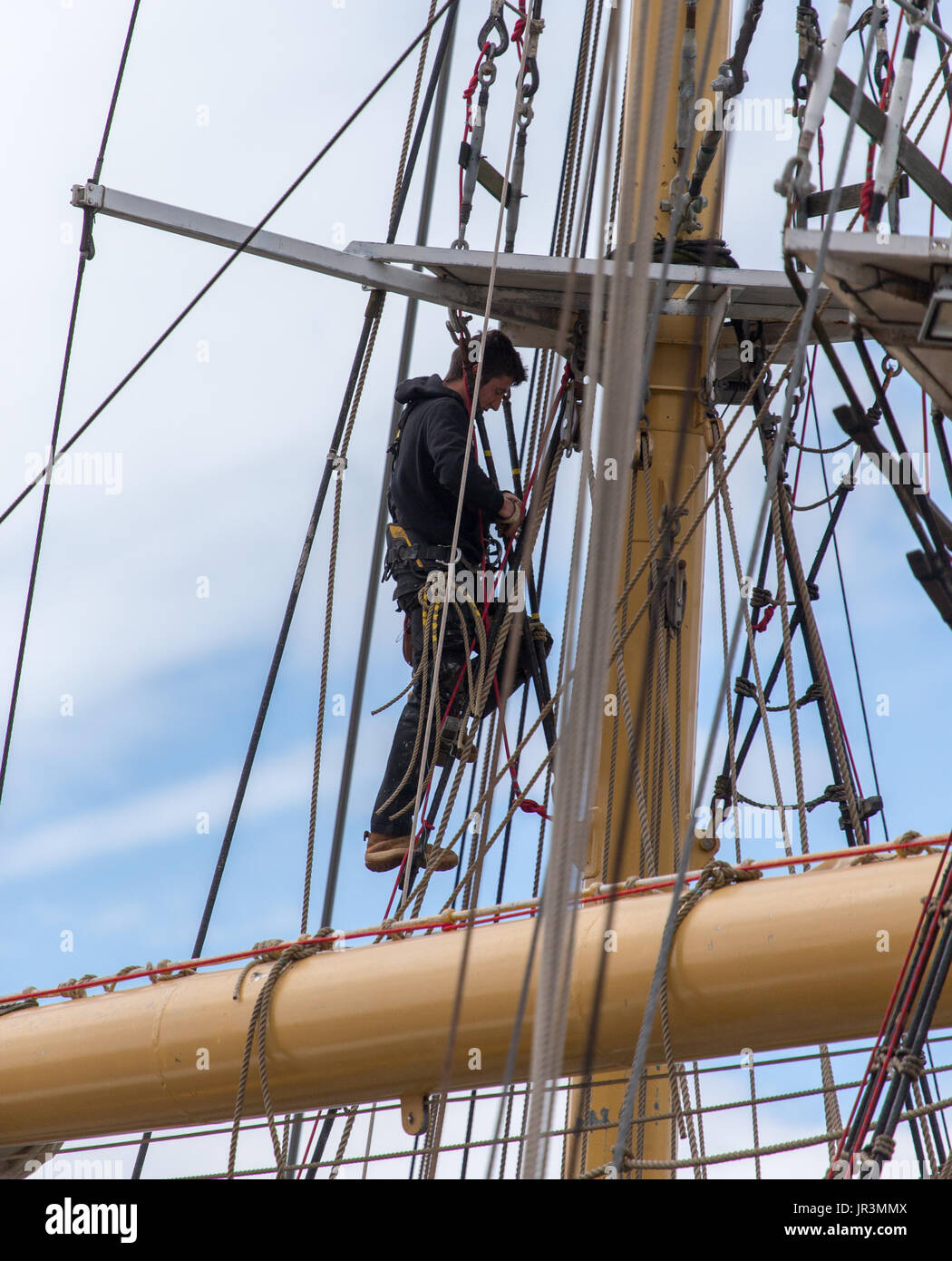 A seaman on a sail training ship working aloft on rigging repairs Stock ...