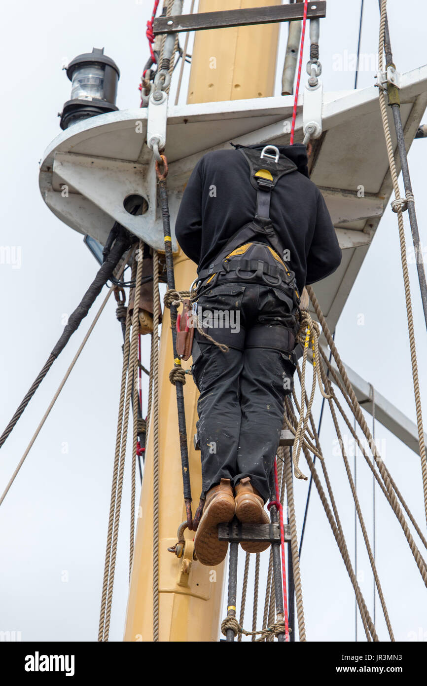 A seaman on a sail training ship working aloft on rigging repairs Stock ...
