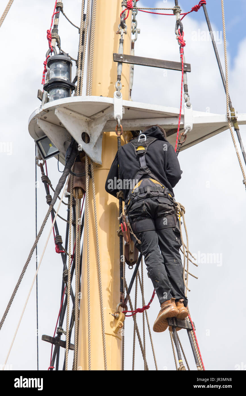 A seaman on a sail training ship working aloft on rigging repairs Stock ...