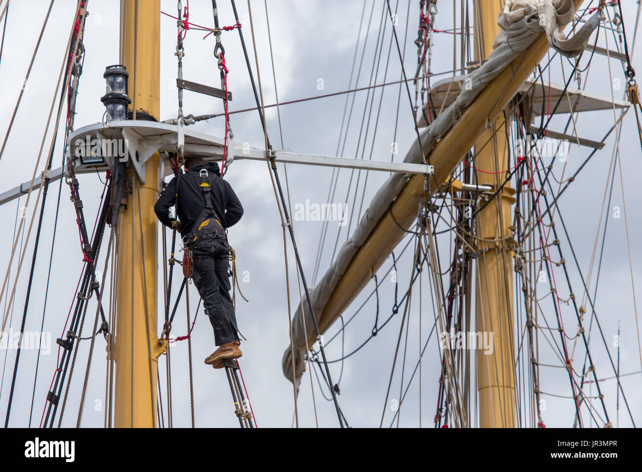 A seaman on a sail training ship working aloft on rigging repairs Stock ...