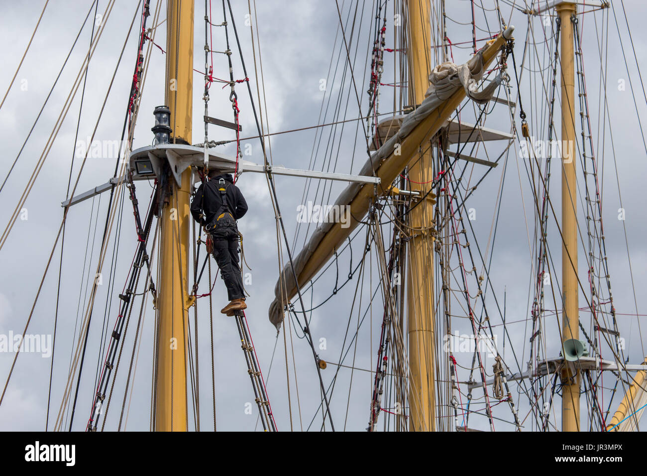 A seaman on a sail training ship working aloft on rigging repairs Stock ...