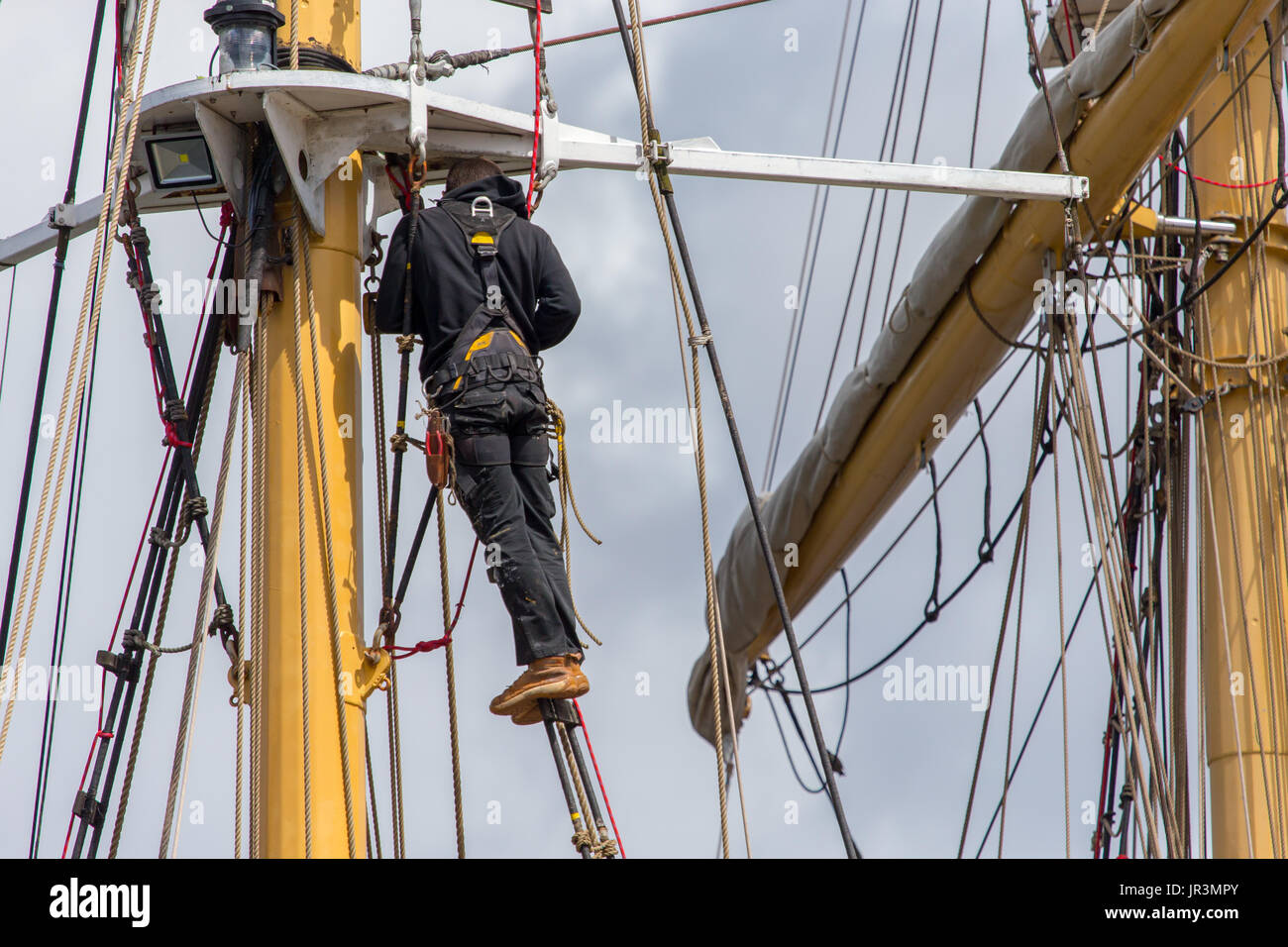 A seaman on a sail training ship working aloft on rigging repairs Stock ...