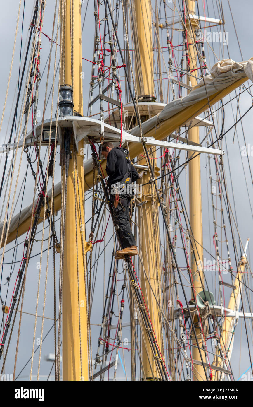 A seaman on a sail training ship working aloft on rigging repairs Stock ...