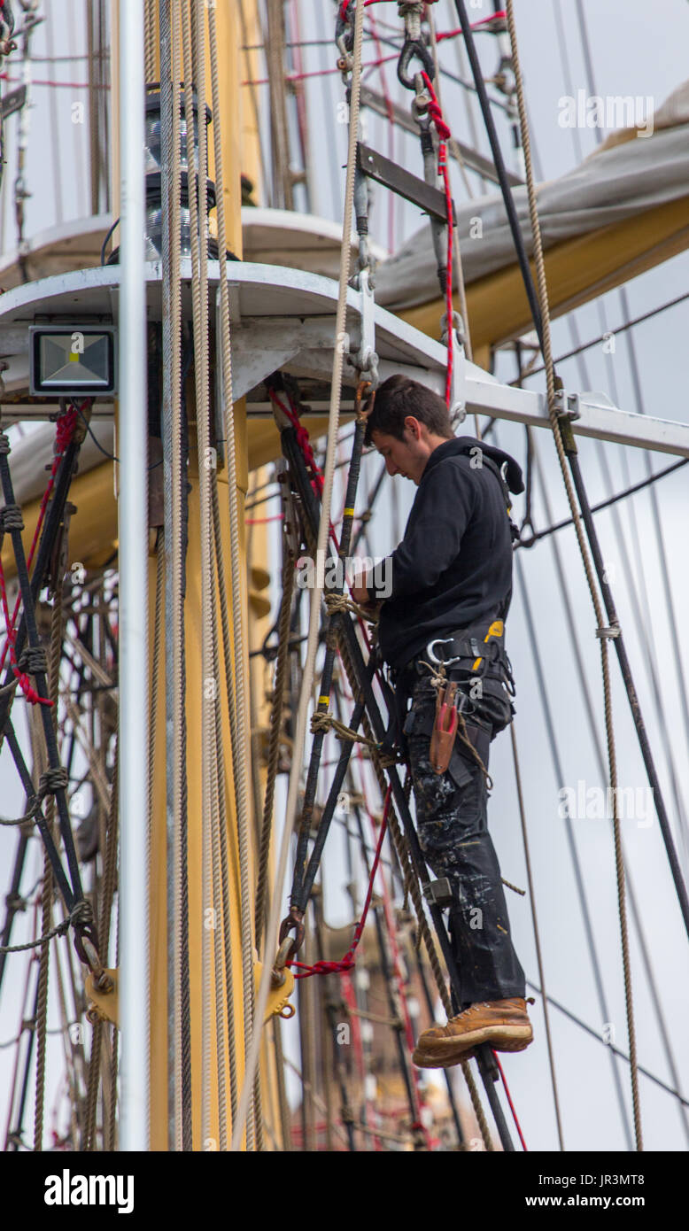 A seaman on a sail training ship working aloft on rigging repairs Stock ...