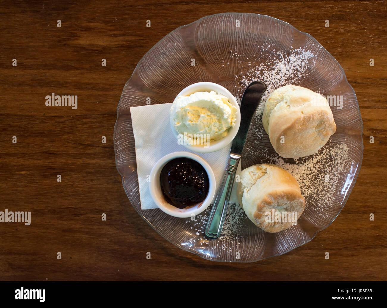 Freshly baked scone cakes served on glass plate with cream and jam ...