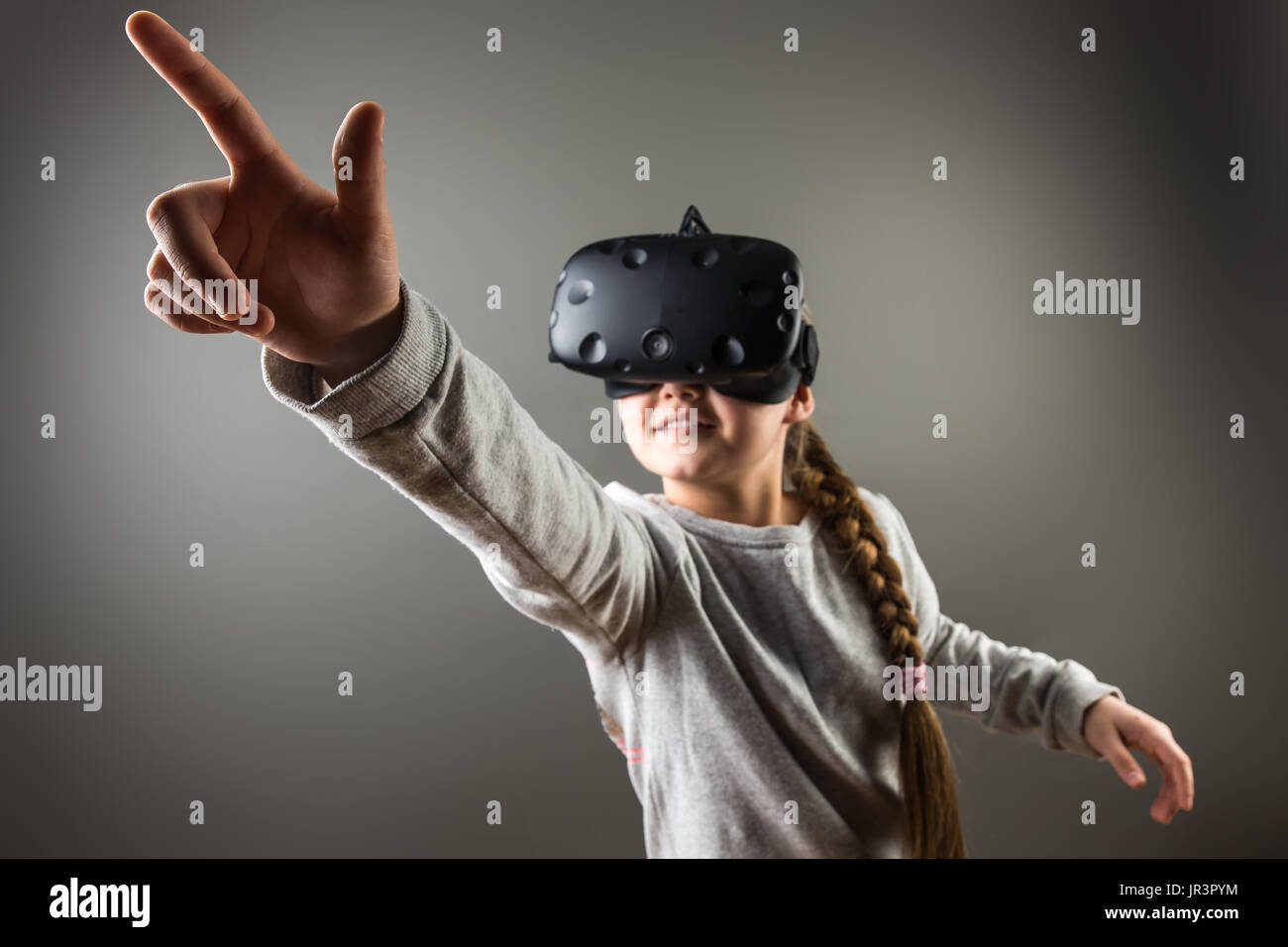 girl wearing virtual reality goggles standing on grey background. VR ...