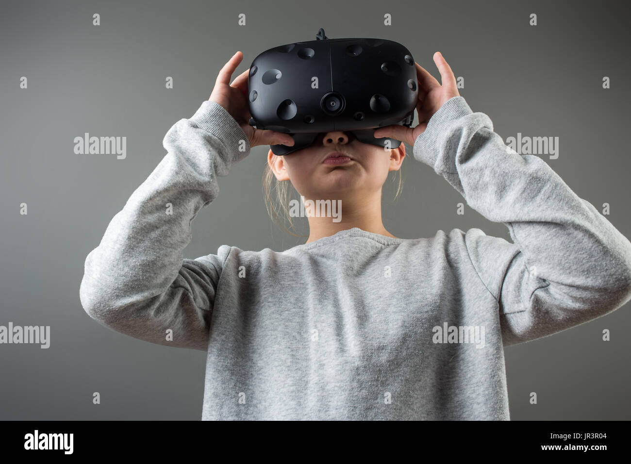 girl wearing virtual reality goggles standing on grey background. VR ...