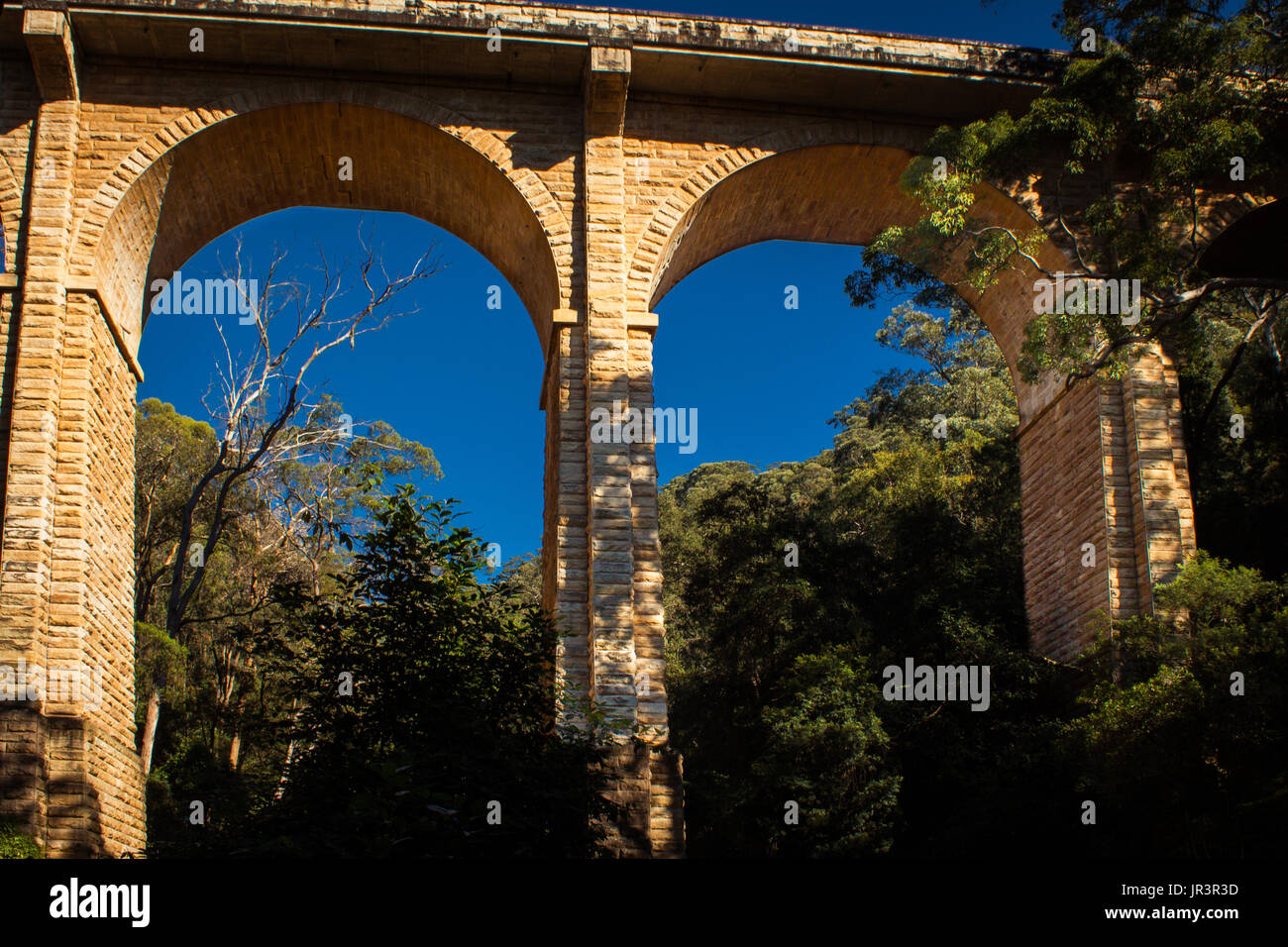 Old sandstone brick arched viaduct bridge with trees and blue sky Stock ...