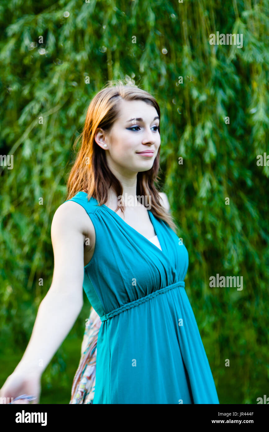 Beautiful girl is in front of a willow tree. Carefree, happy and joyful ...