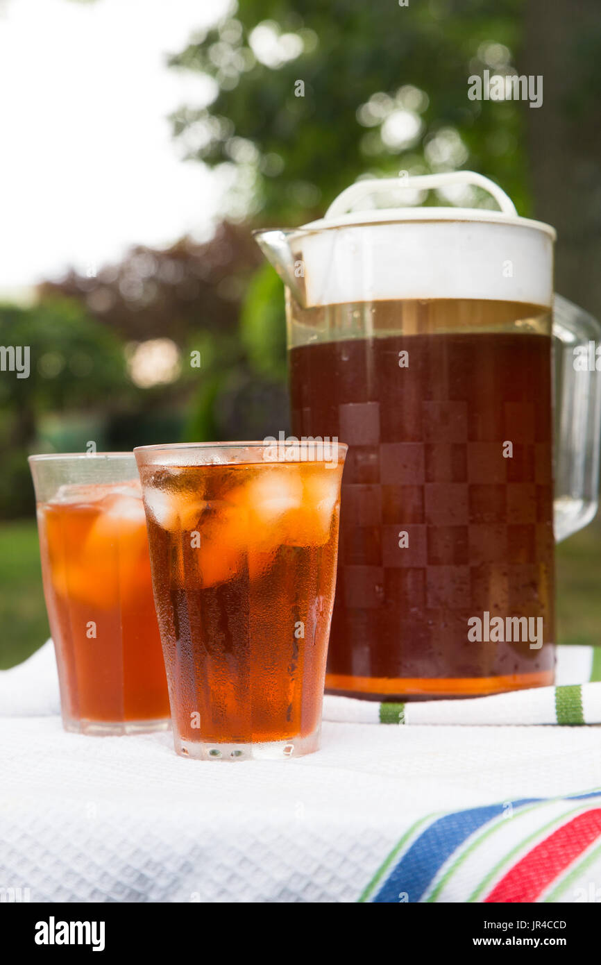 Pitcher of iced tea and a glass in outdoor backyard summer setting ...