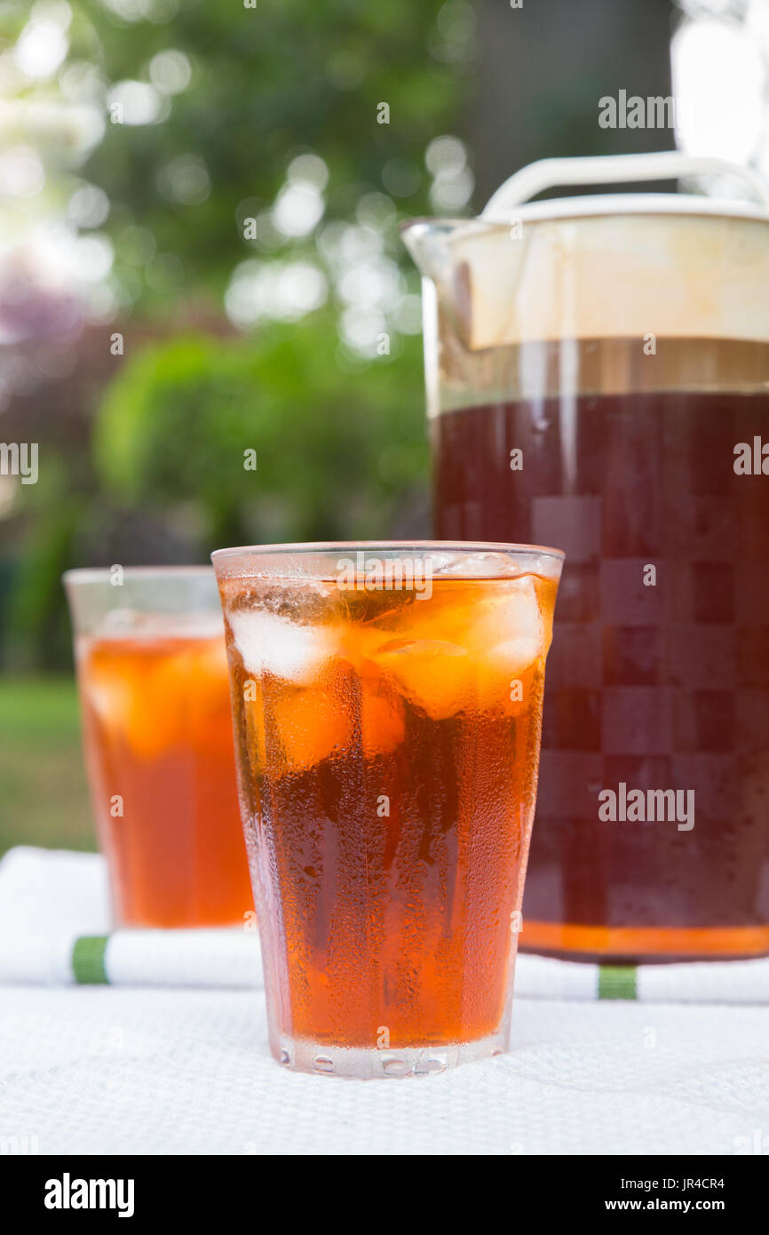Pitcher of iced tea and a glass in outdoor backyard summer setting ...