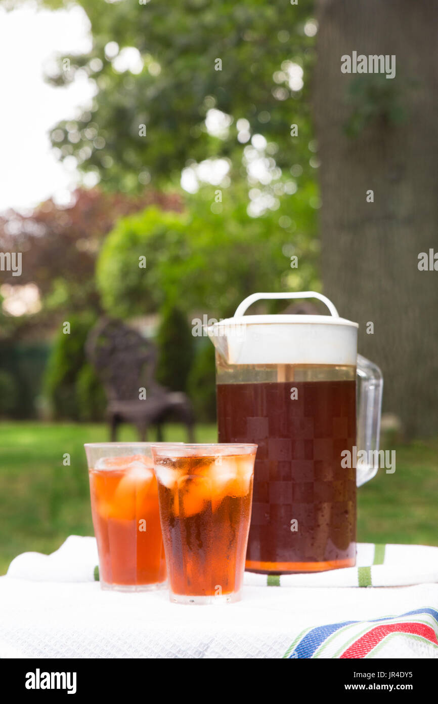 Pitcher of iced tea and a glass in outdoor backyard summer setting ...