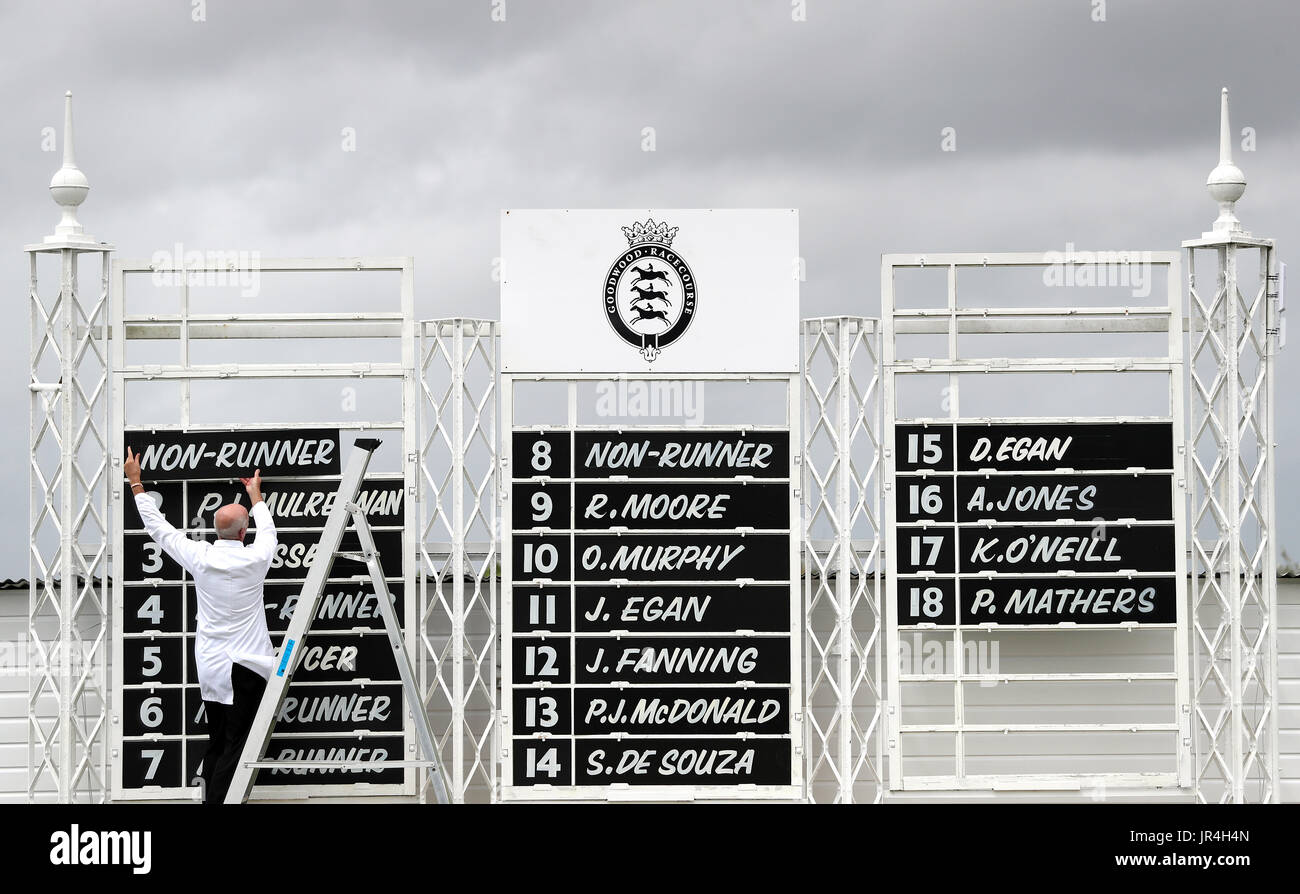 A member of the course staff changes the jockey names on a riders board ...
