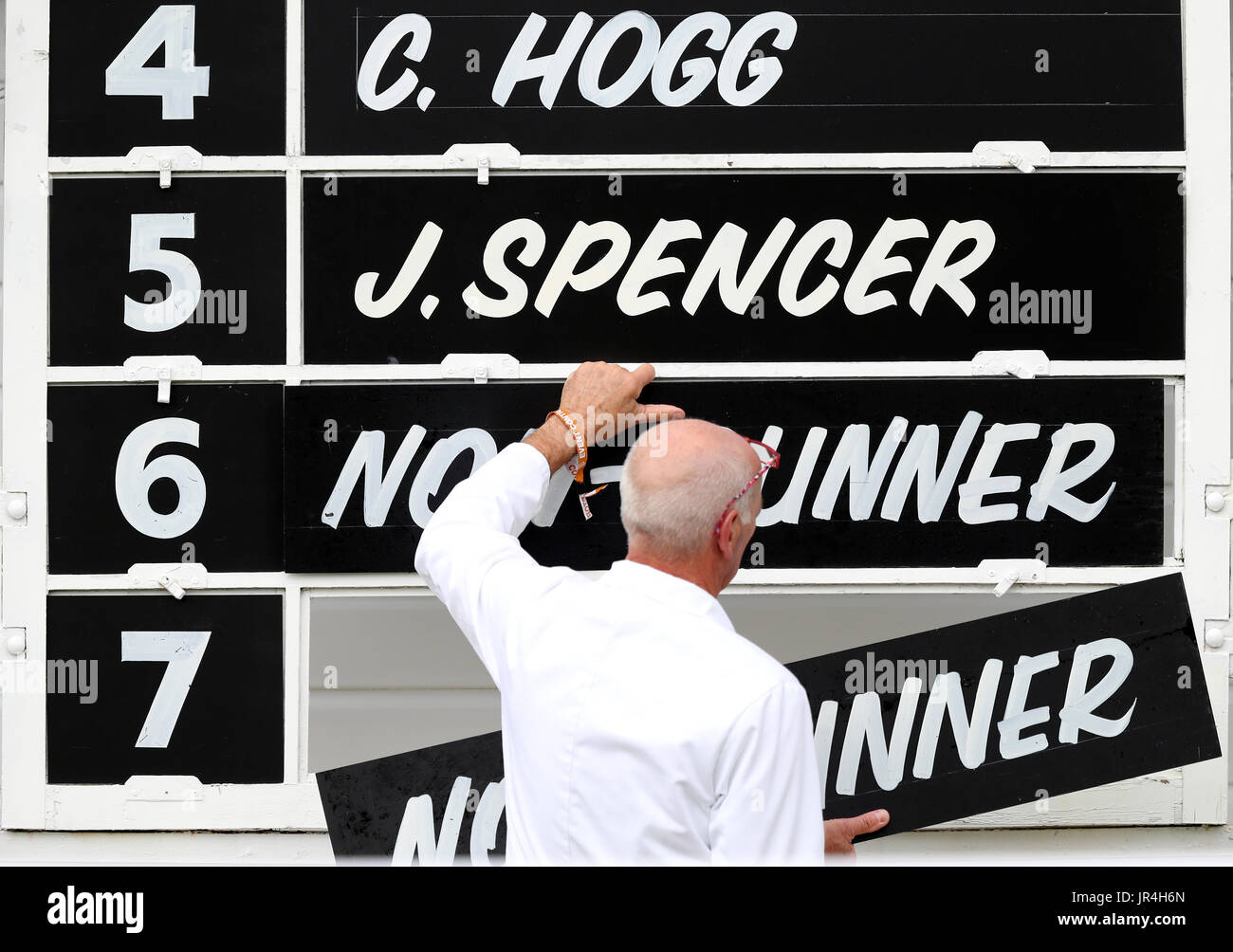 A member of the course staff changes the jockey names on a riders board ...