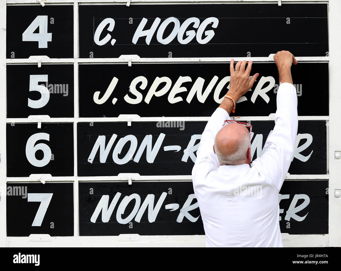 A member of the course staff changes the jockey names on a riders board ...