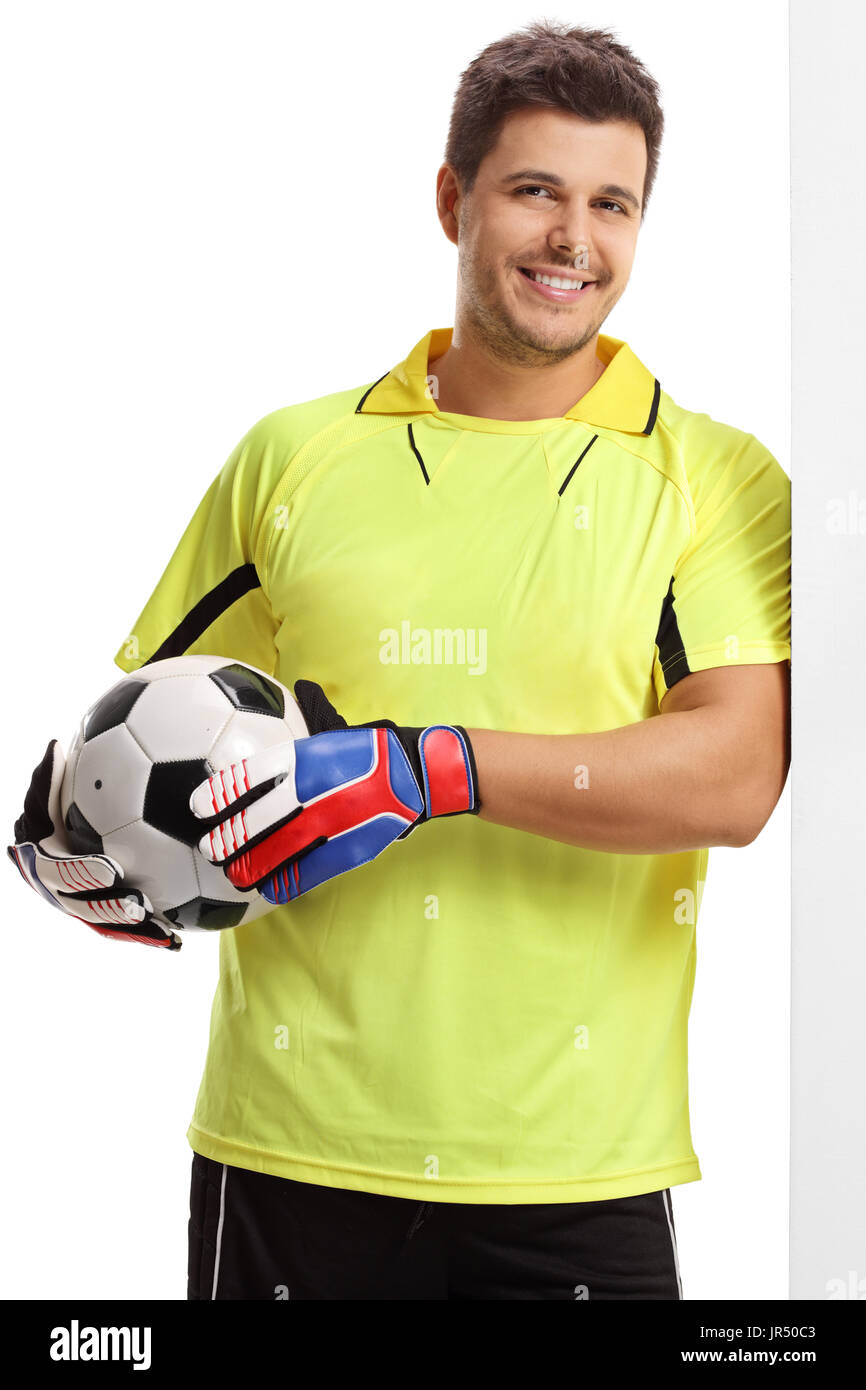 Goalkeeper with a football leaning against a wall isolated on white ...