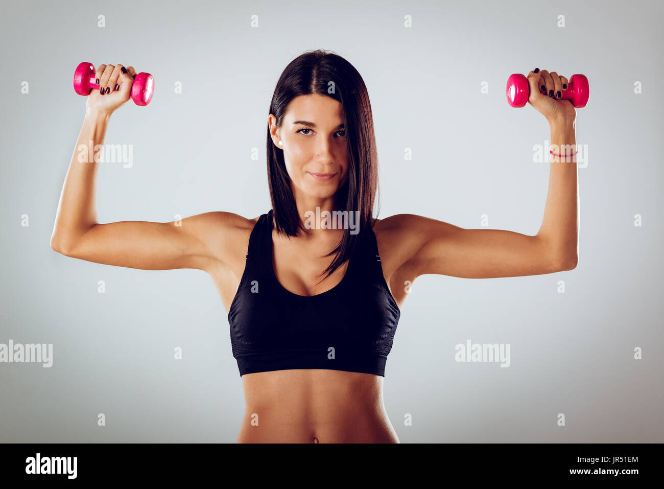 Attractive muscular young woman doing exercise with dumbbells Stock ...