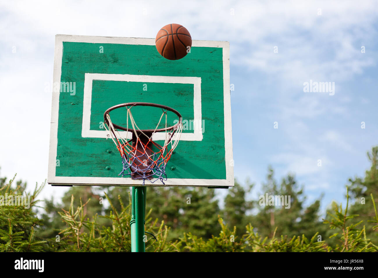 The Basketball hoop in the garden. Ball is being trown in the hoop ...