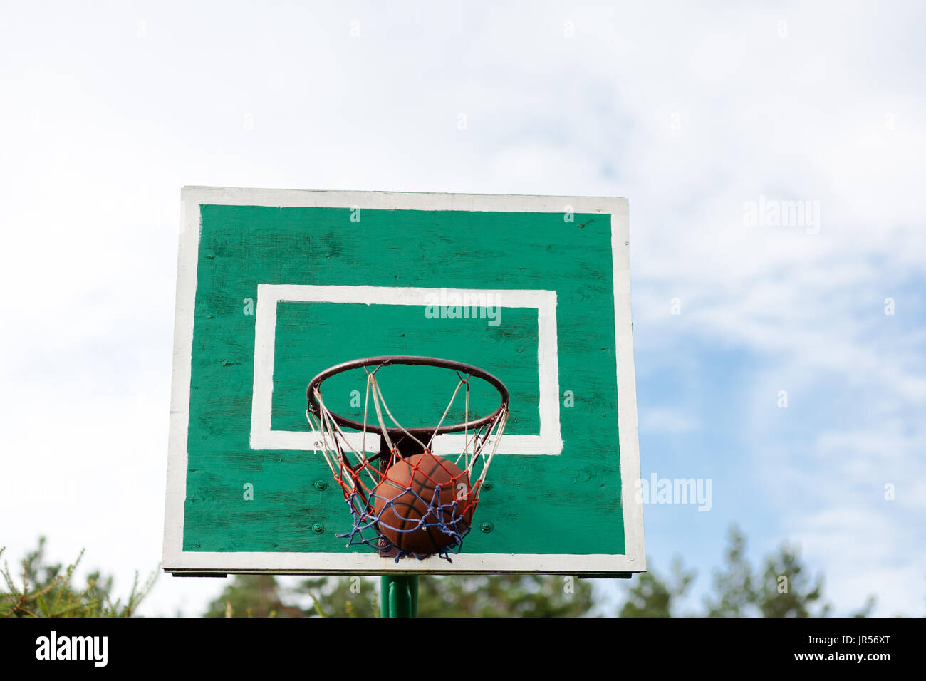 The Basketball hoop in the garden. Ball is being trown in the hoop ...
