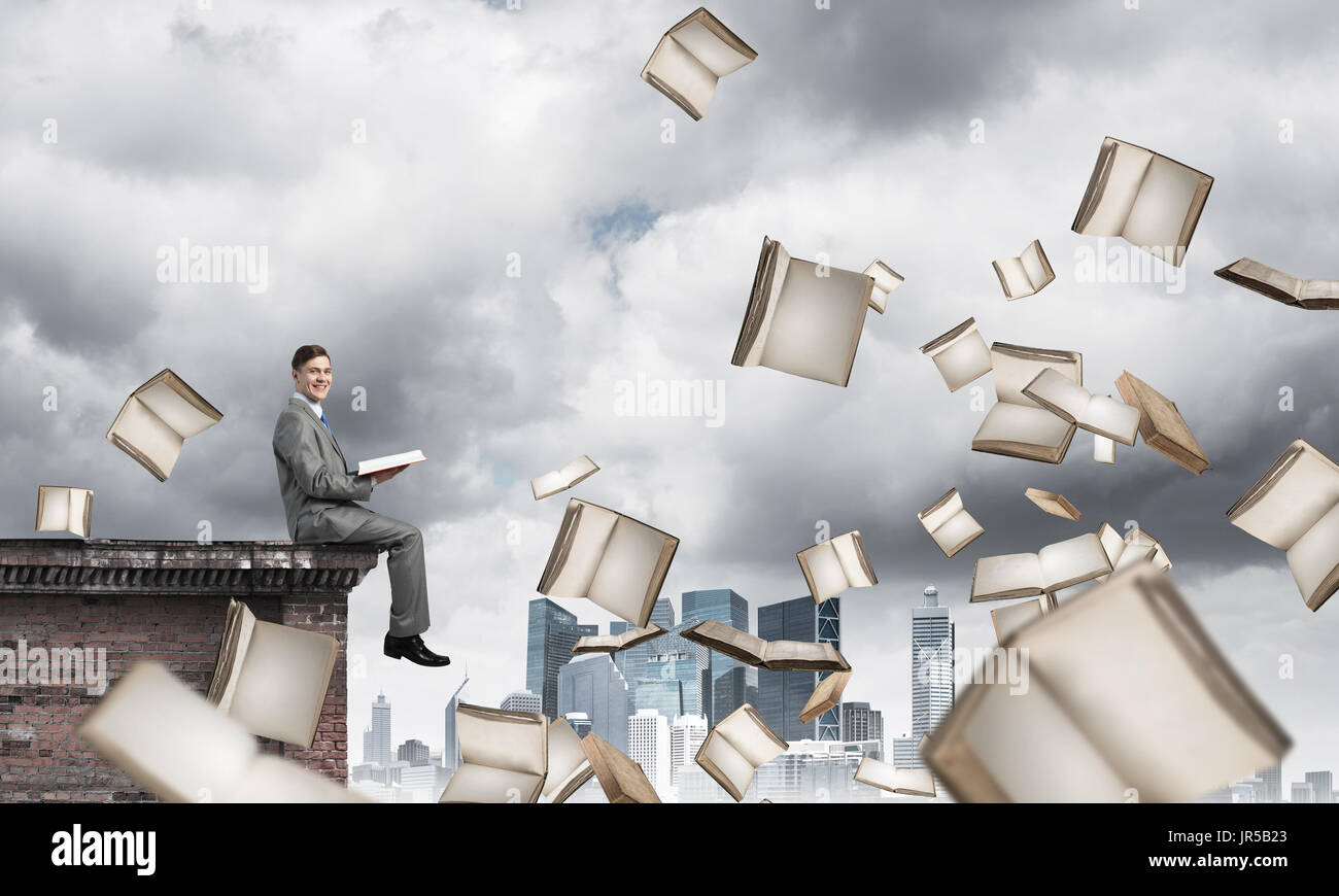 Man on roof reading book and many of them flying in air Stock Photo - Alamy