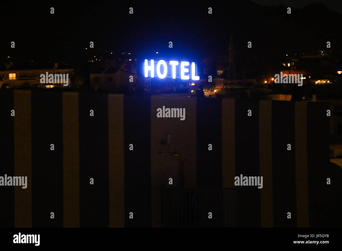 A blue hotel sign is illuminated in the night Stock Photo - Alamy