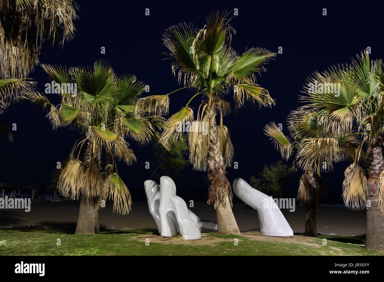 A statue of an open hand holding a palm tree on the beach front in ...