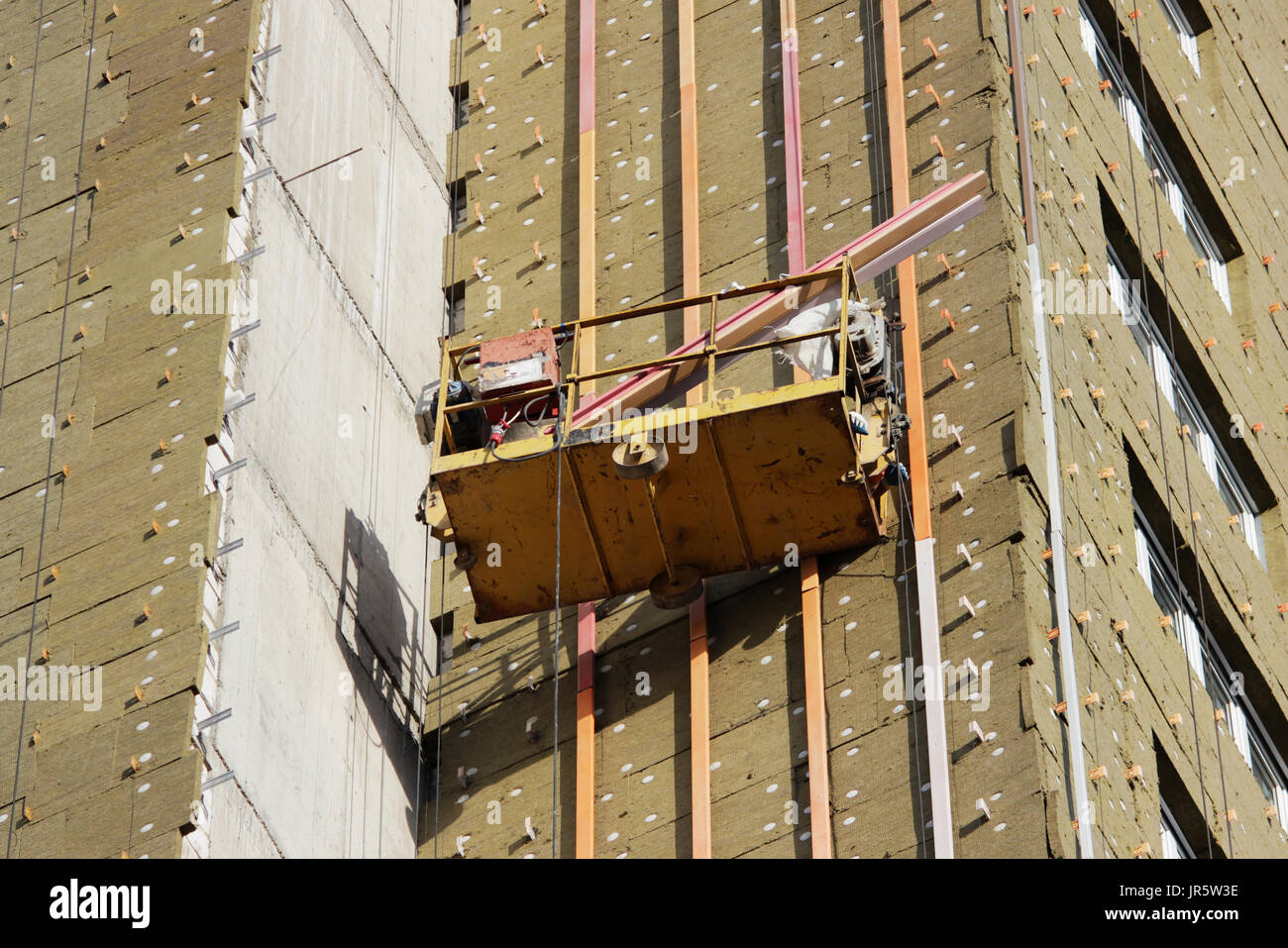 worker in yellow suspended cradle mounts environmental boards for ...