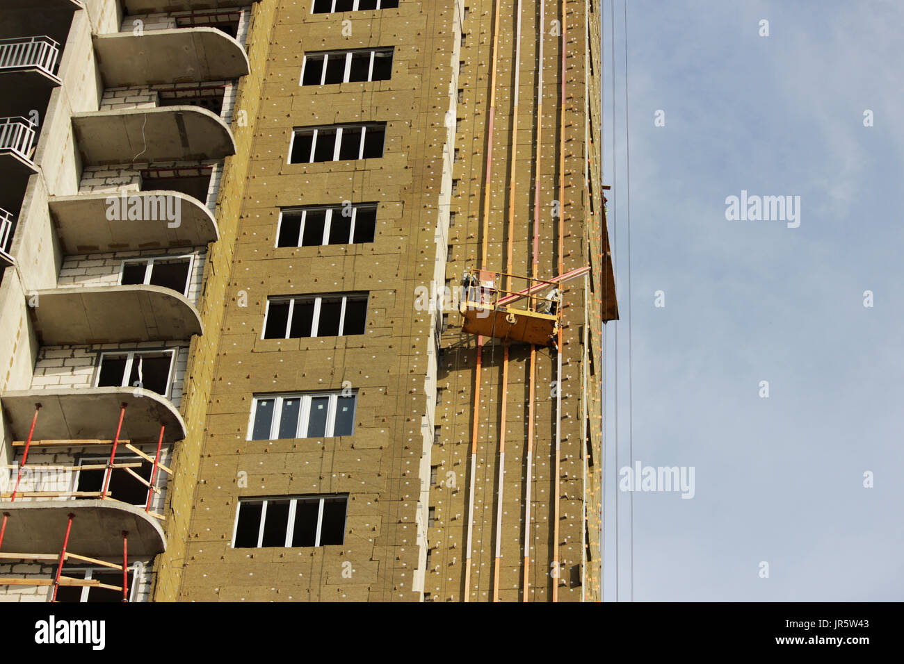 worker in yellow suspended cradle mounts environmental boards for ...