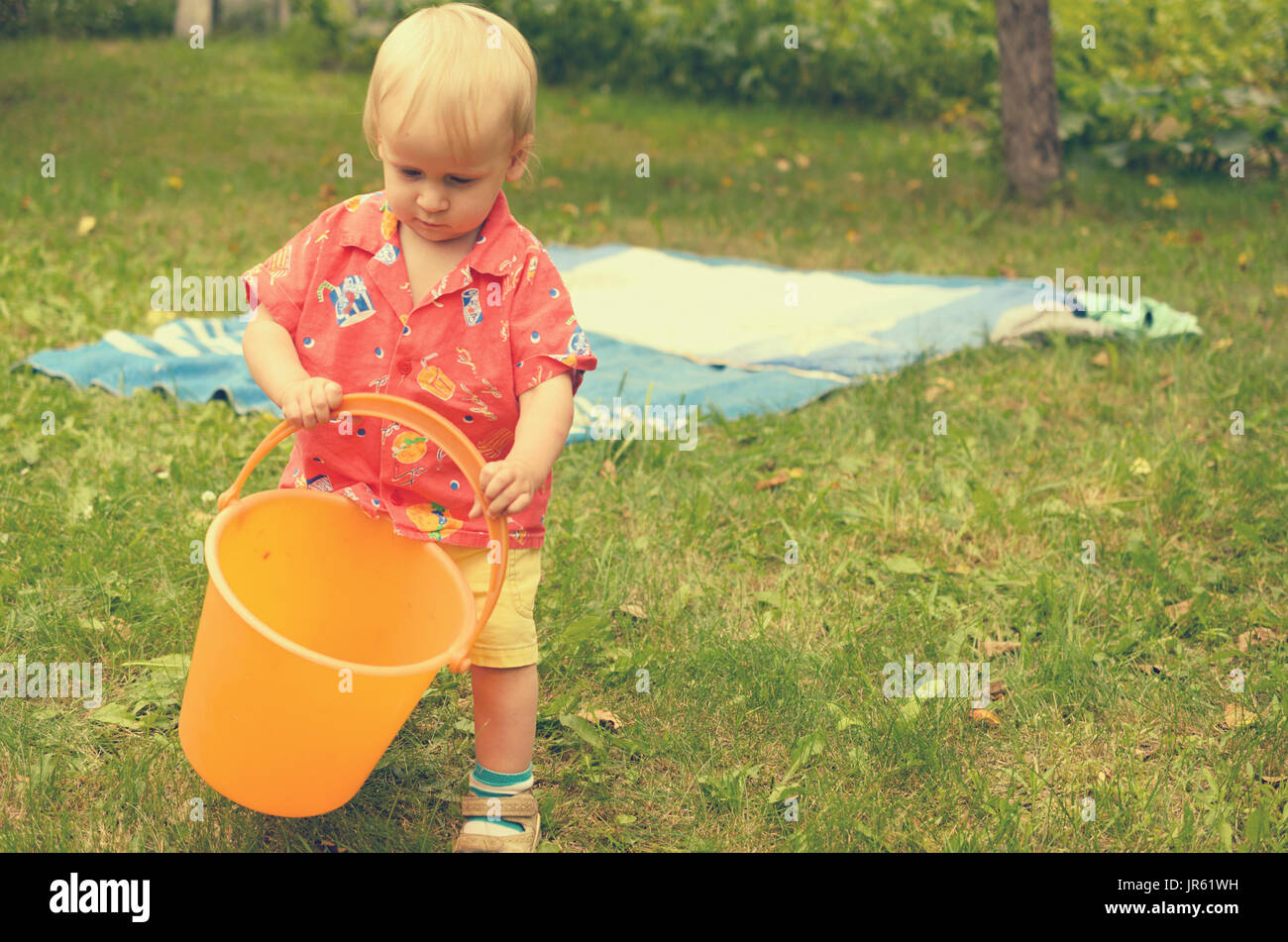 Little girl is playing with an empty bucket Stock Photo - Alamy